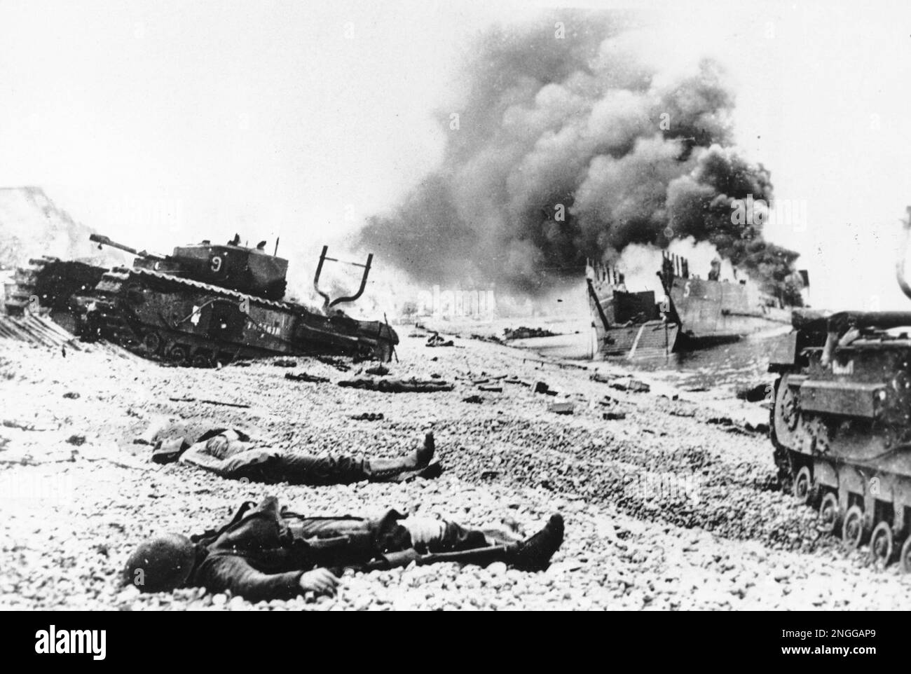 With a burning landing craft in the background and disabled tanks next ...