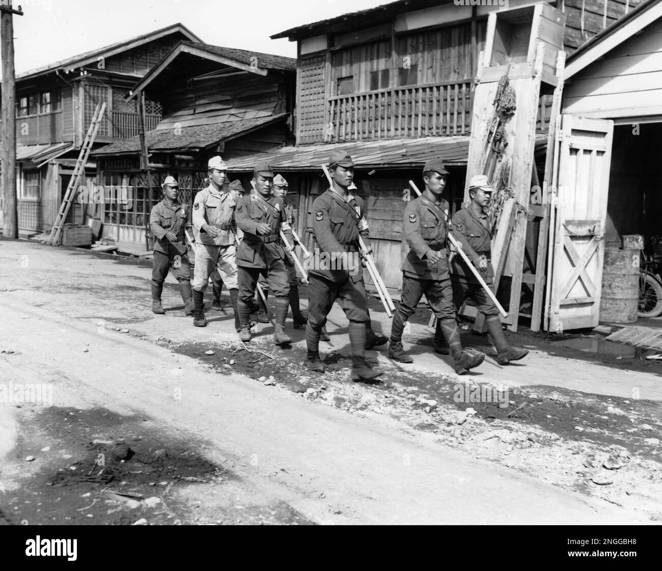 A Japanese naval shore patrol marches down a street in Ominato, Japan ...