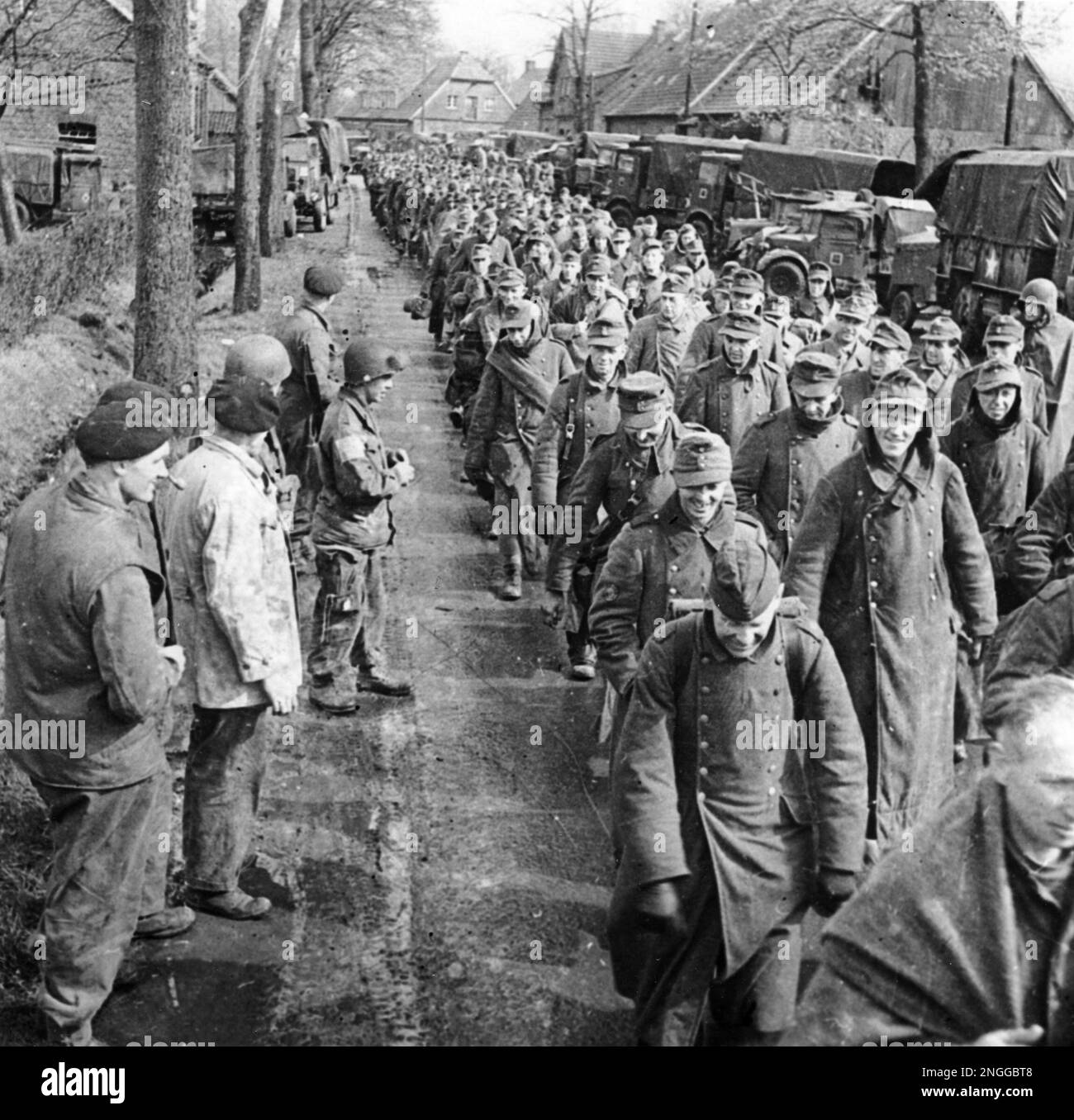Standing along a roadside, British and American soldiers watch a long ...