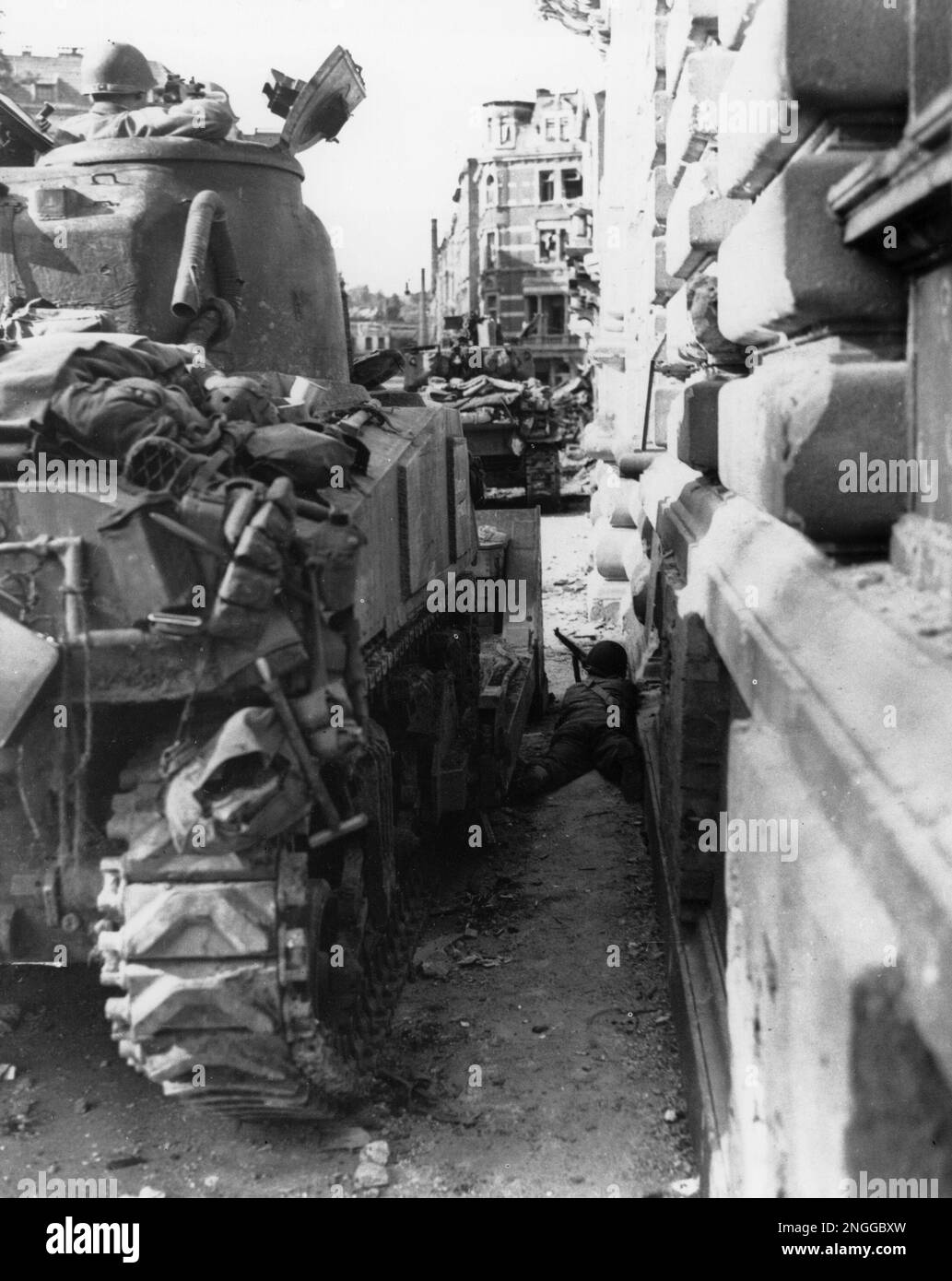 A U.S. Army sniper uses a tank for cover while firing and advancing ...