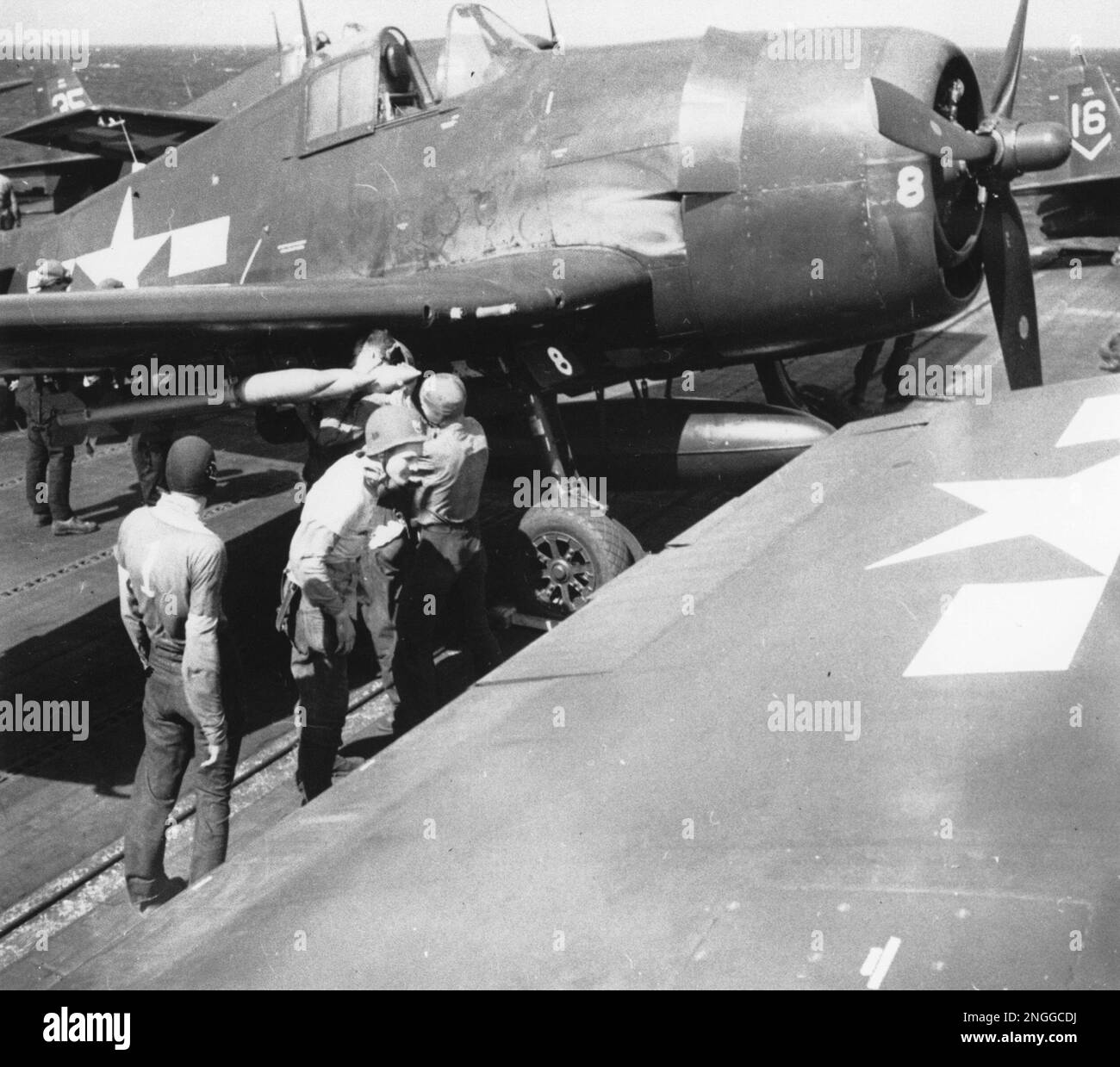 Crewmen aboard a U.S. Navy carrier are seen as they install rockets on a F6F Grumman Hellcat in ...