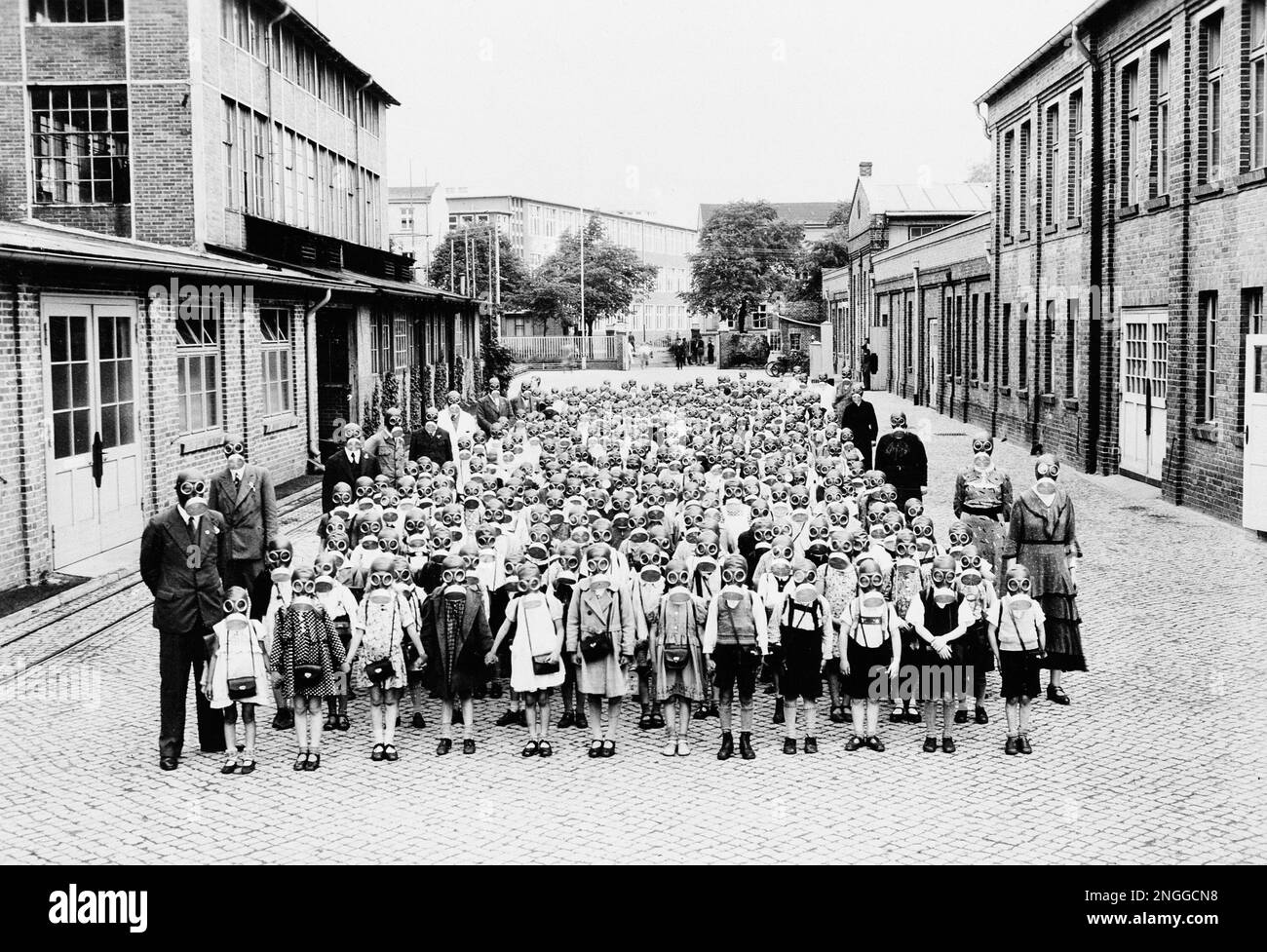 German school teachers and children wear gas masks as they are drilled ...