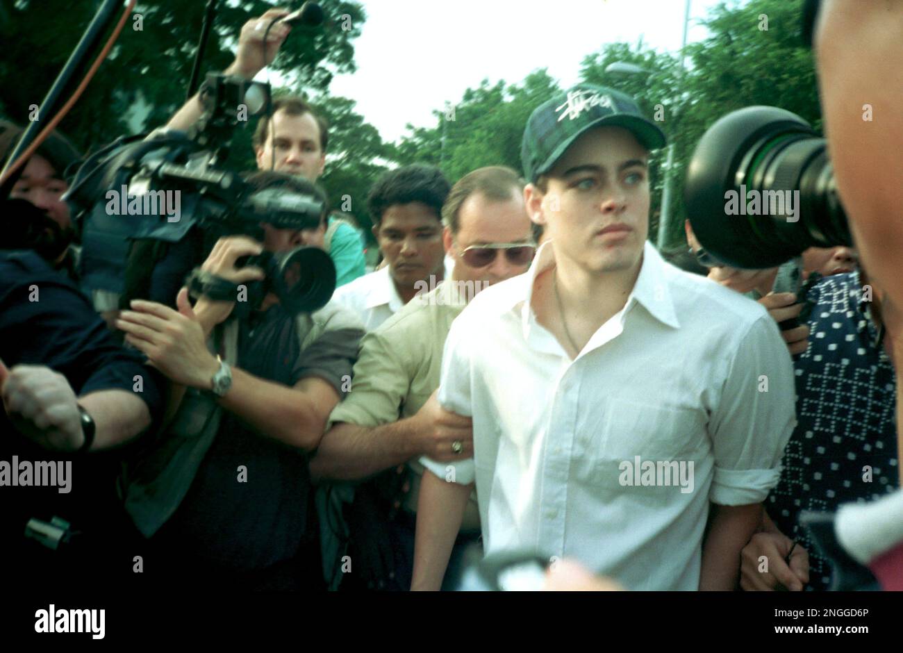 American Michael Fay, 19, accompanied by his father George, behind ...