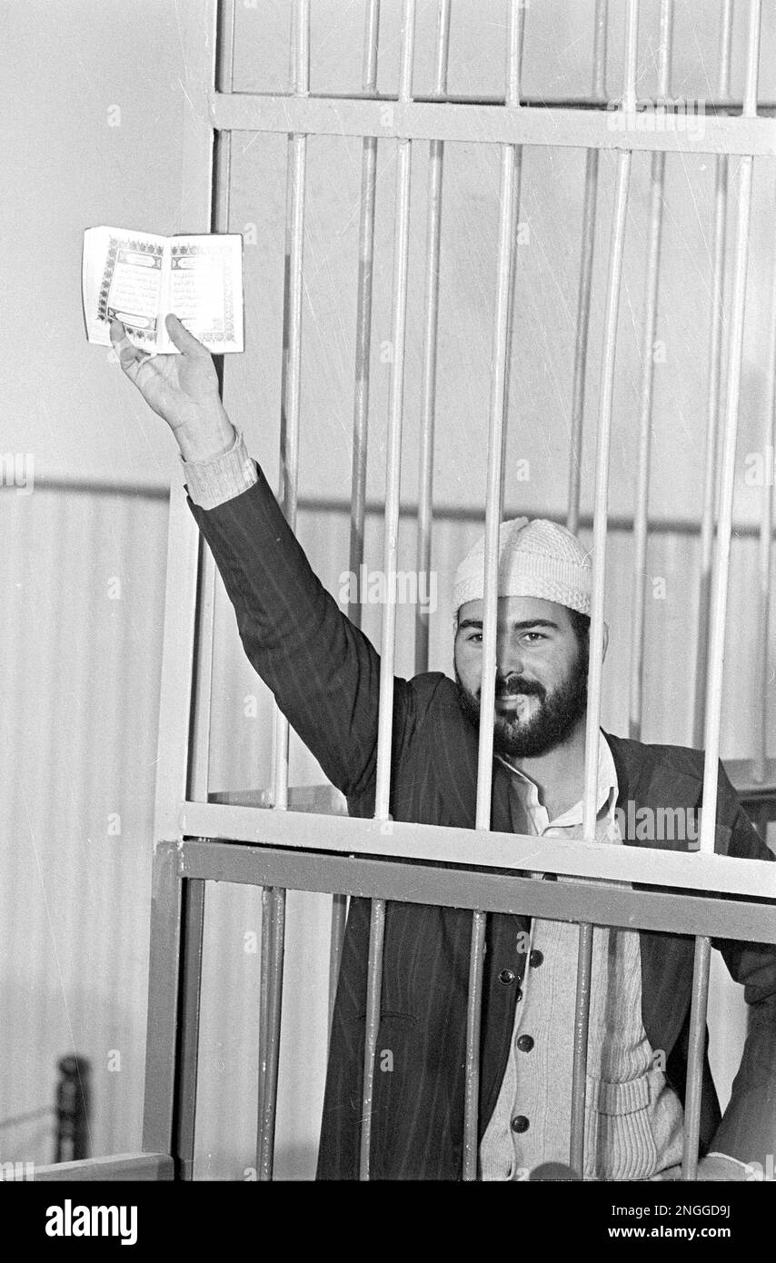 Khaled al-Islambouli holds an open Koran from behind court cell bars ...