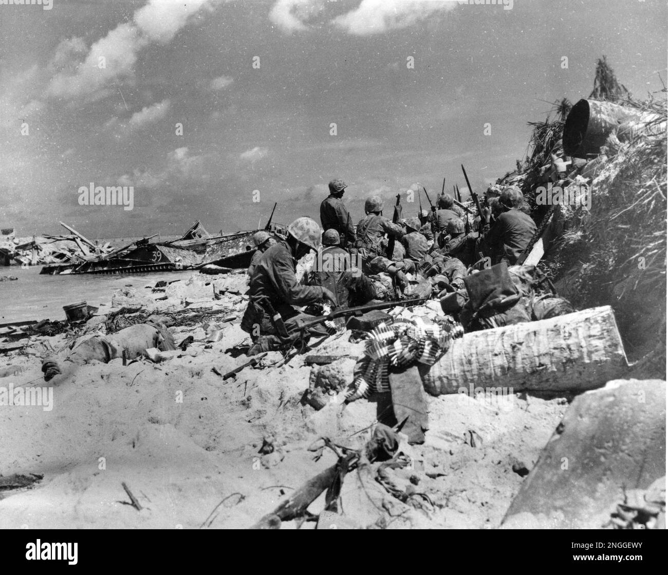 U.S. Marines find cover behind a bank on the edge of a lagoon on Tarawa ...