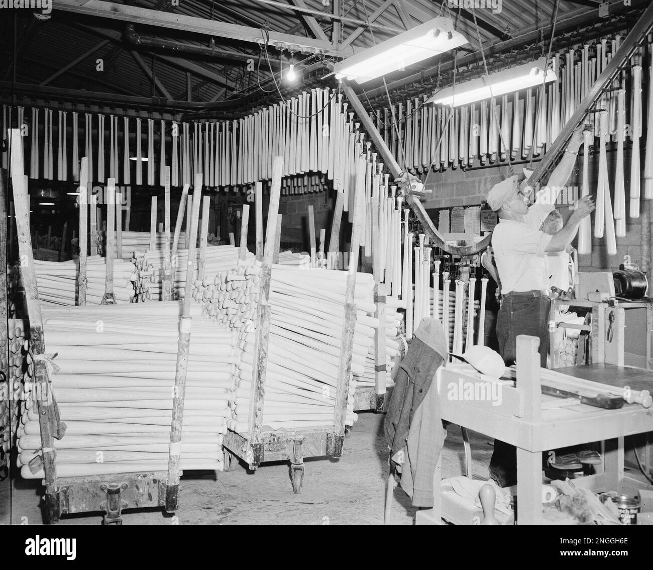 A worker places a wooden baseball bat on the assembly line at the ...
