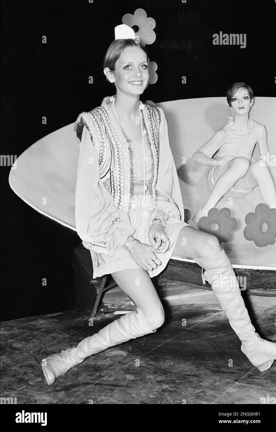 British fashion model Twiggy poses beside the portrait figure of ...