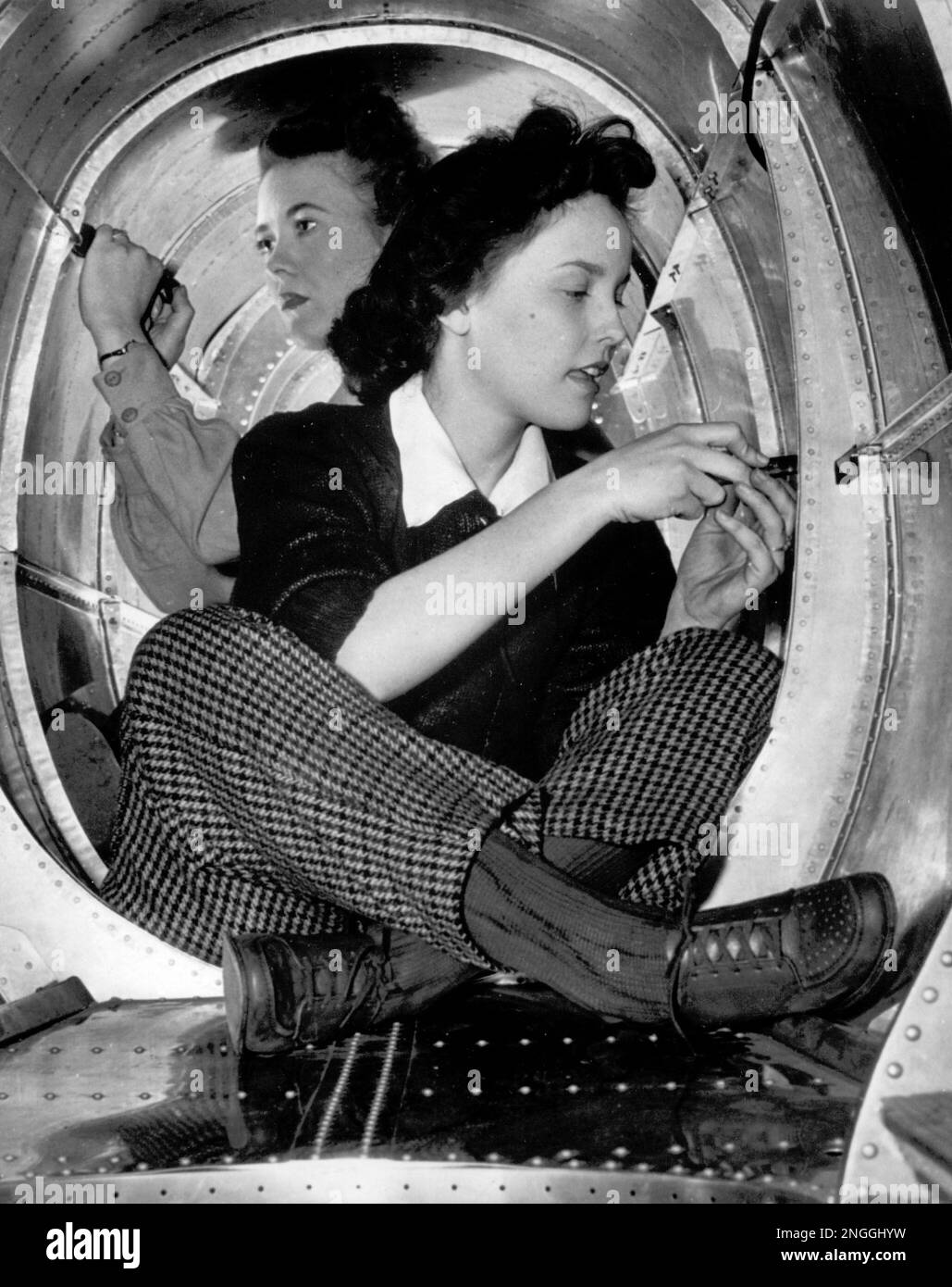 Two women are seen working the production line at Grumman Aircraft ...