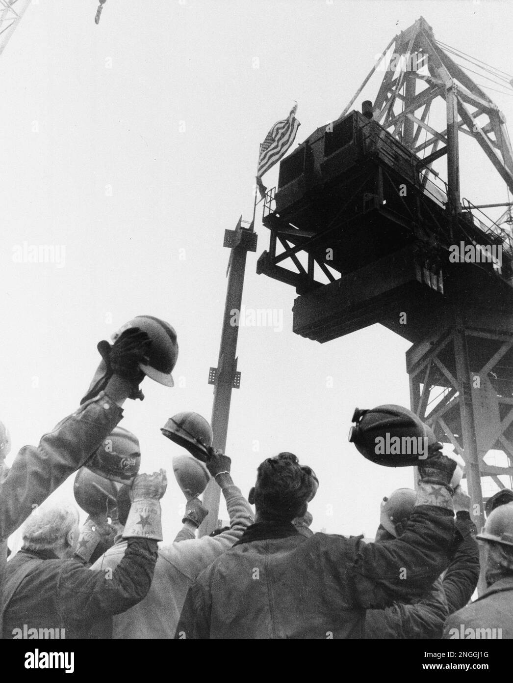Construction workers raise their hats in salute as the American flag is ...