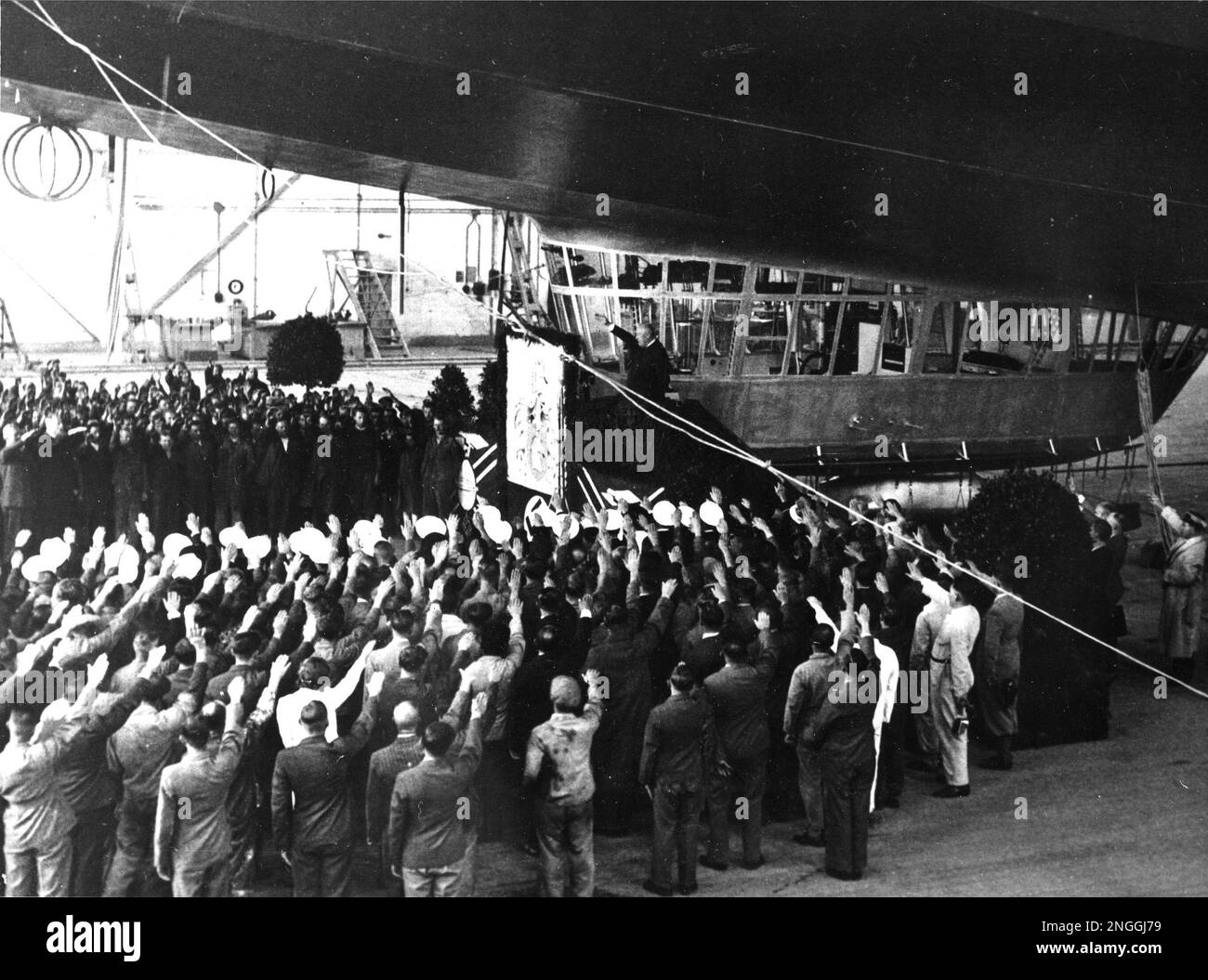 In a short ceremony, aviator Dr. Hugo Eckener, on the speaker's rostrum, baptizes the new ...