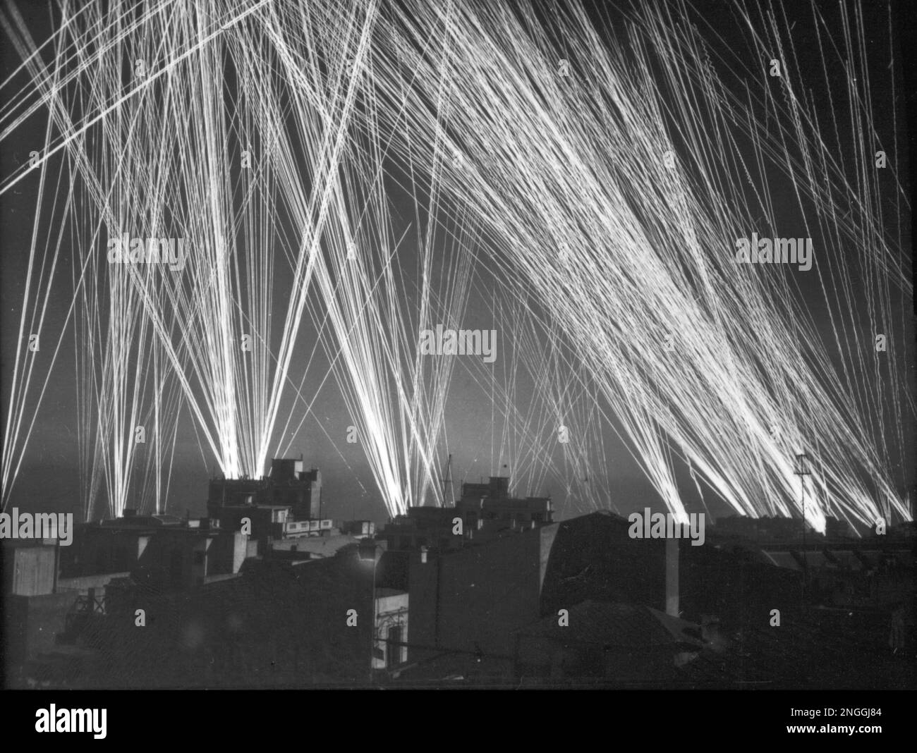 The sky over Algiers is lit up by searchlight beams and heavy ack-ack ...