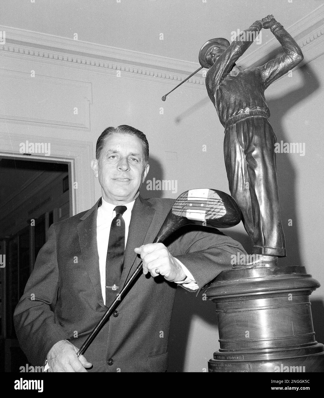 Joseph C. Dey is posing with an outsized golf club next to a statue of ...