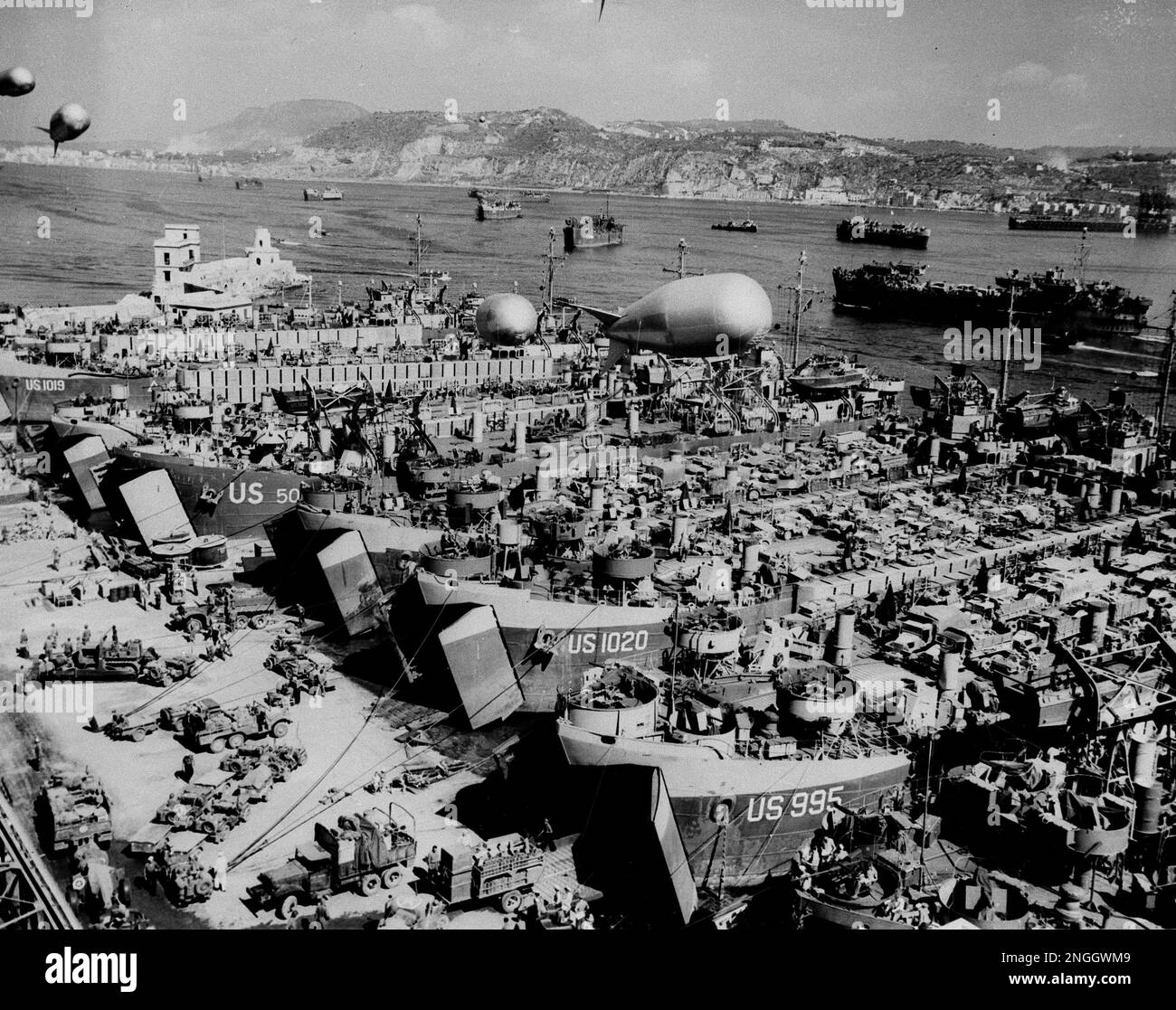 Barrage balloons hover overhead for protection against Nazi air attack as U.S. landing ship ...