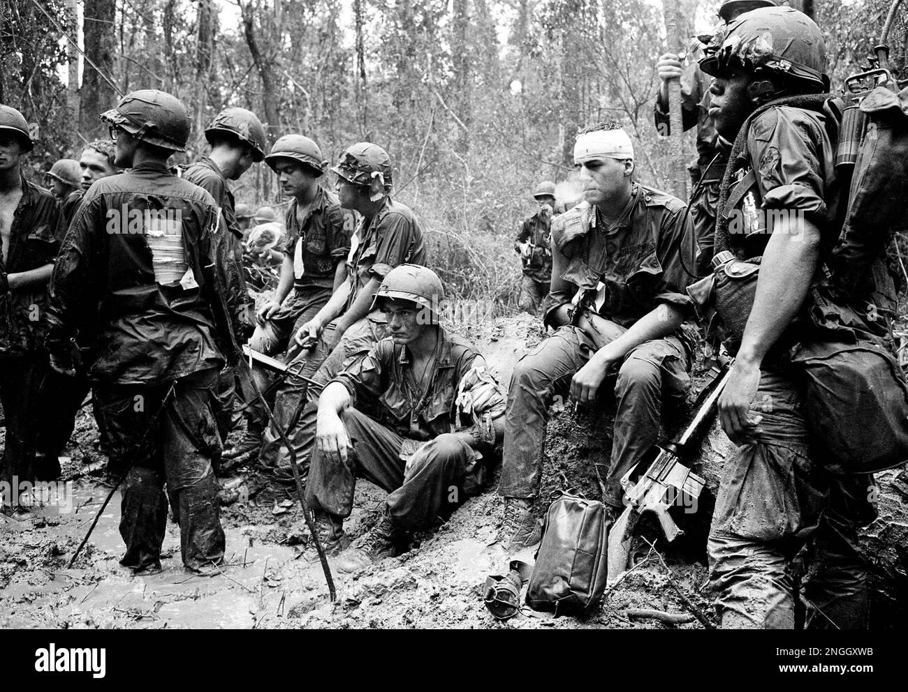 Wounded American G.I.s sit and stand in ankle-deep mud in the monsoon ...