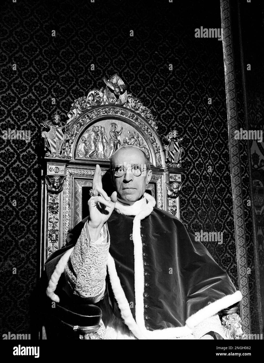 Pope Pius XII, wearing the ring of St. Peter, raises his right hand in ...