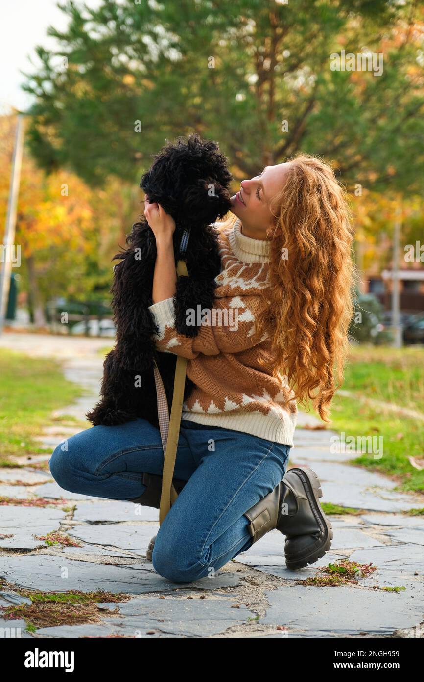 Young woman hugging her black puppy poodle dog in a park Stock Photo ...