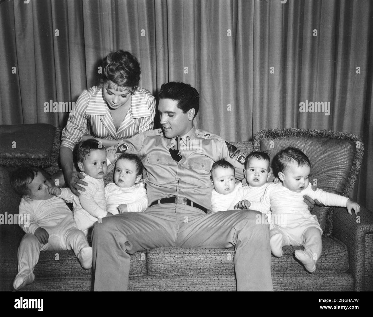 Singer-actor Elvis Presley is shown with six babies who appear in the ...