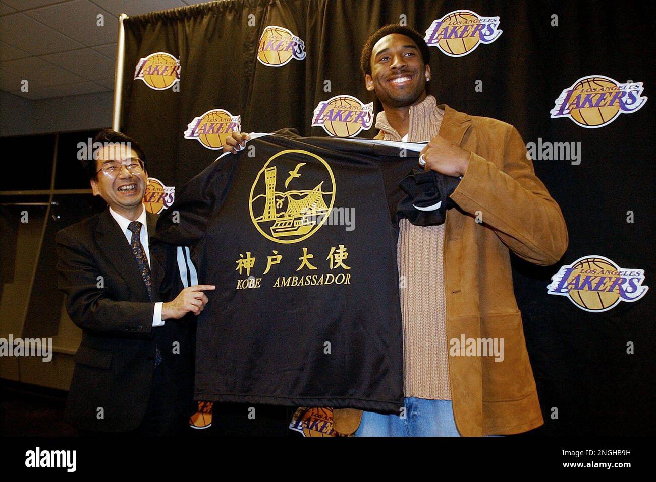 Los Angeles Lakers' Kobe Bryant, right, holds up a warm up jersey ...