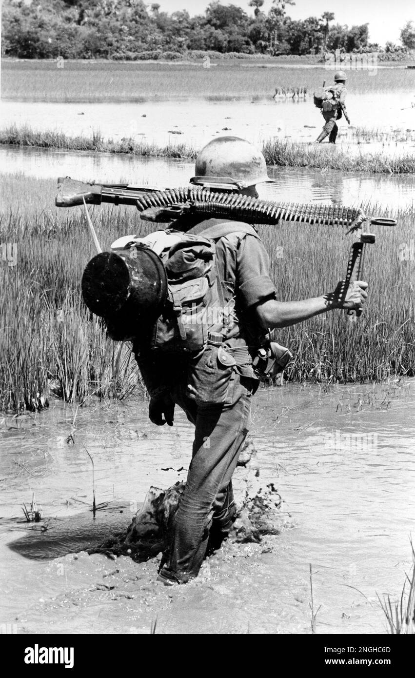 A South Vietnamese soldier moves across a flooded rice-paddy field ...