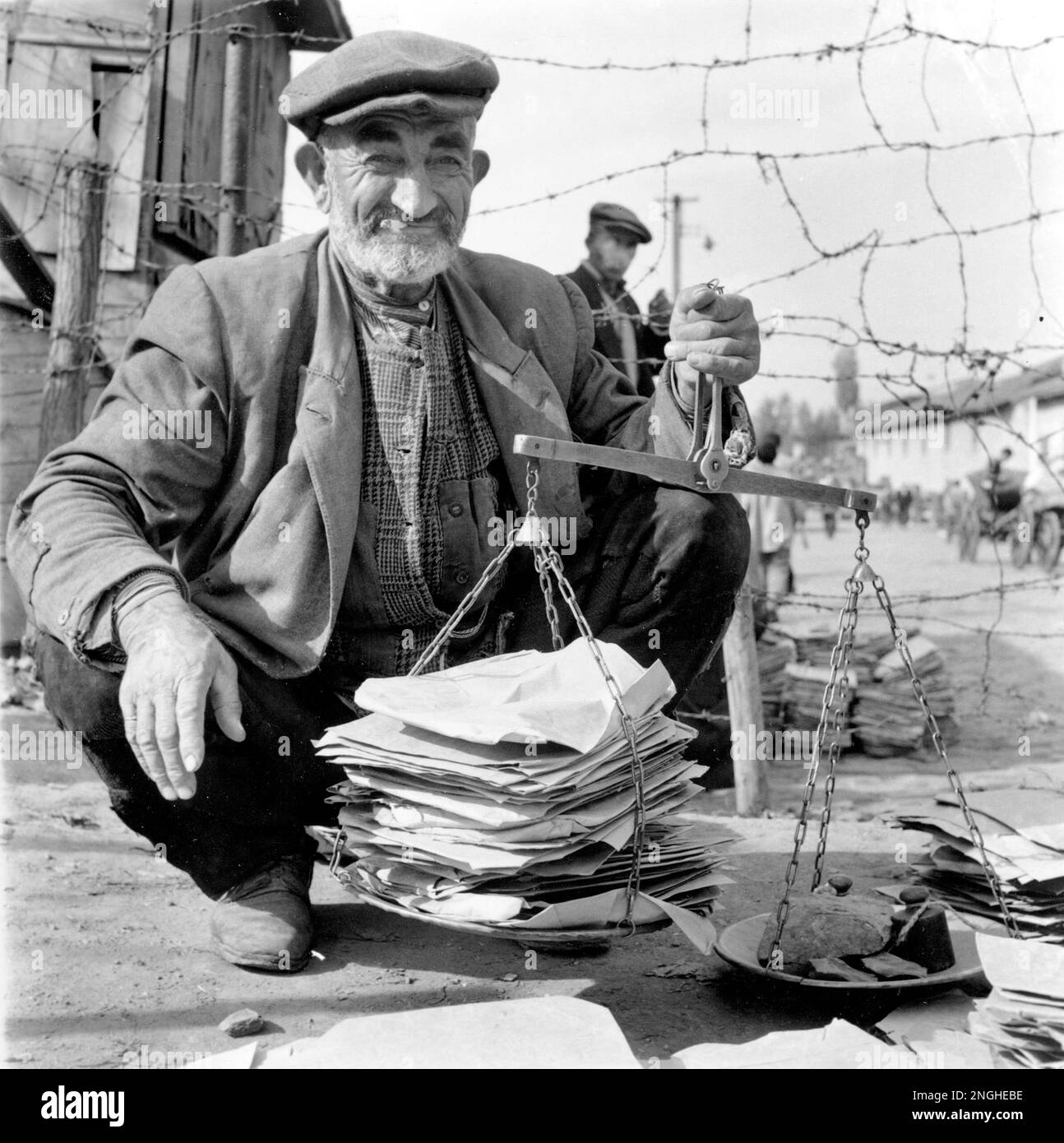A Turkish paper vendor poses with his scale as he waits for customers ...
