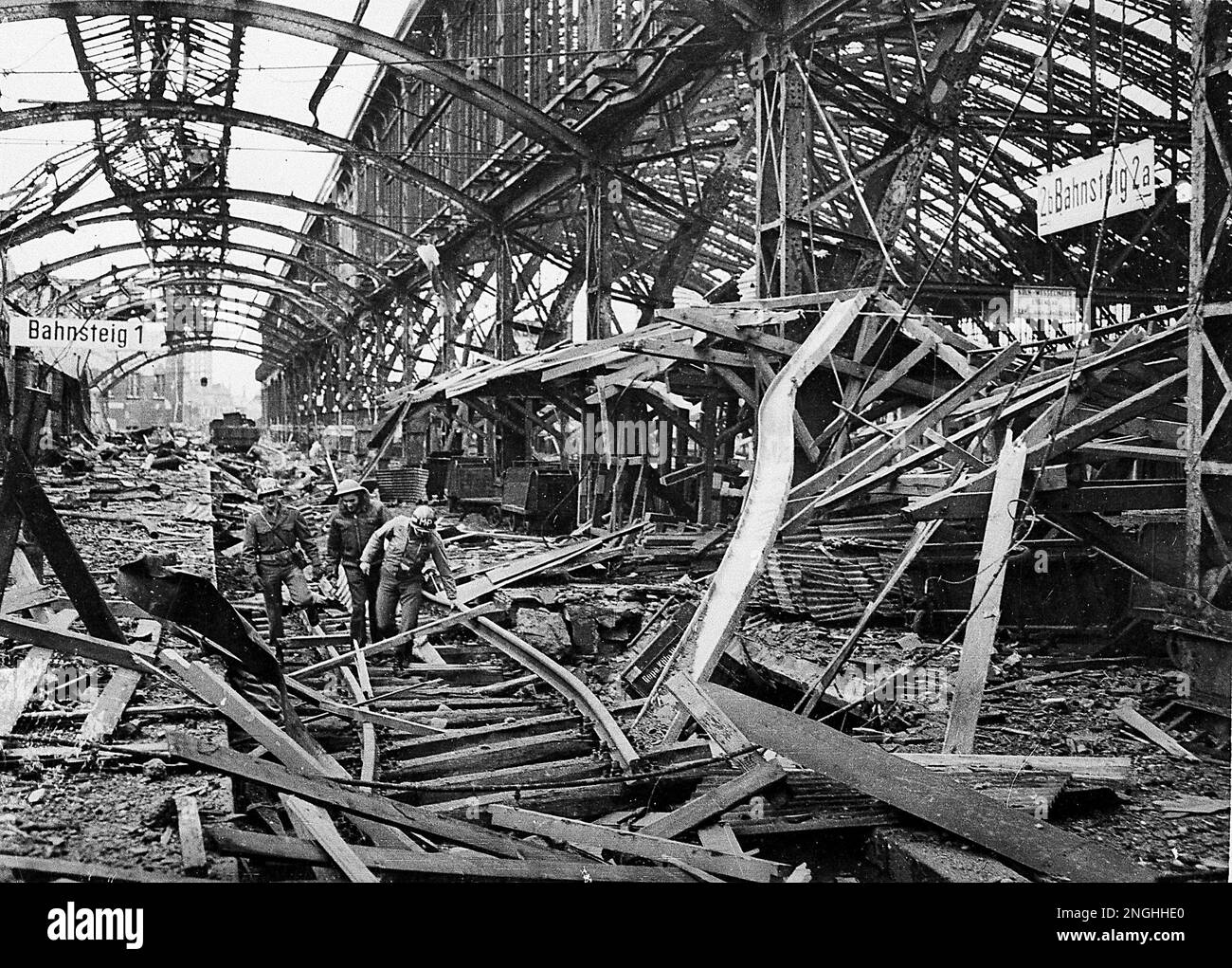 Three Allied soldiers pick their way over the ravaged and twisted track ...