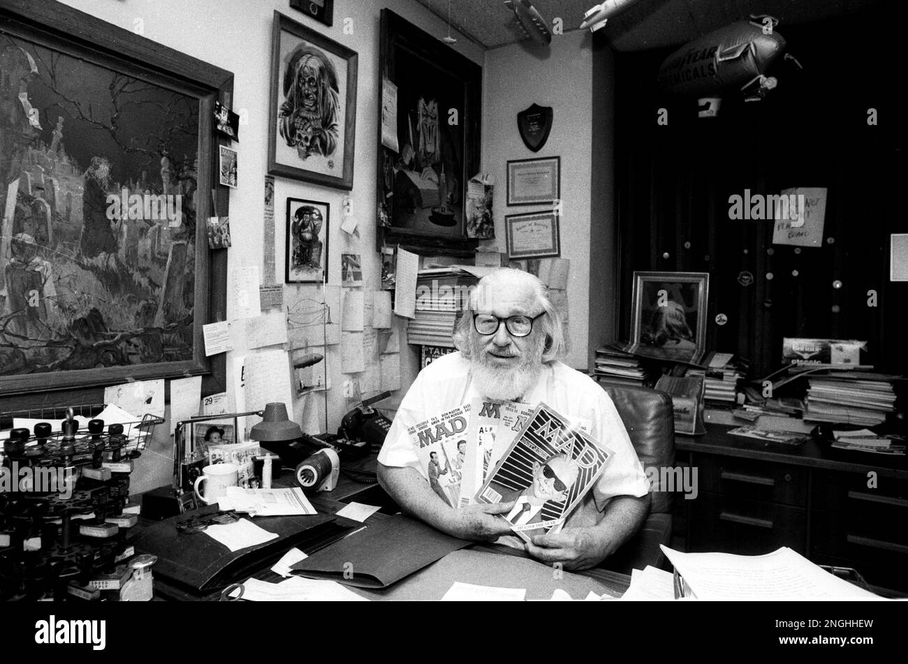 William M. Gaines, publisher of MAD magazine, poses at his office desk ...