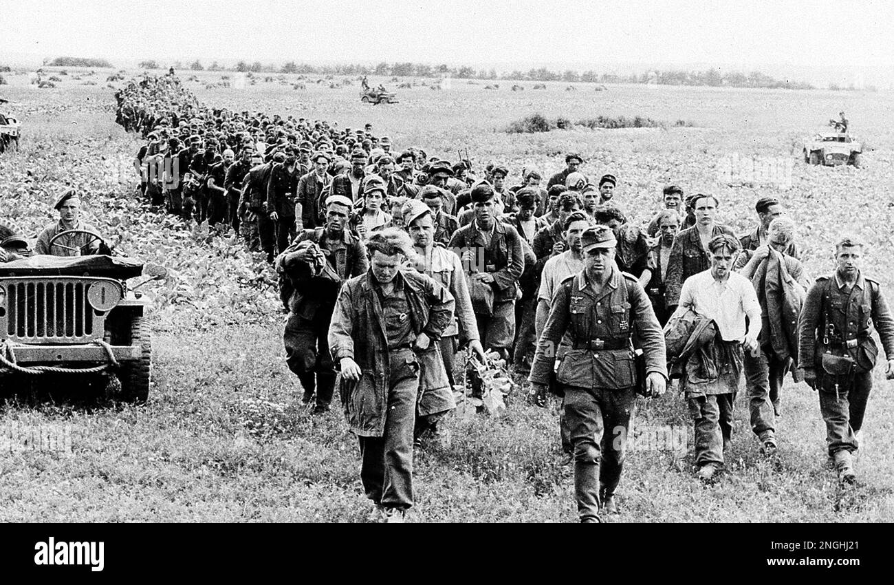 A long line of German prisoners of war march on a field on their way to ...