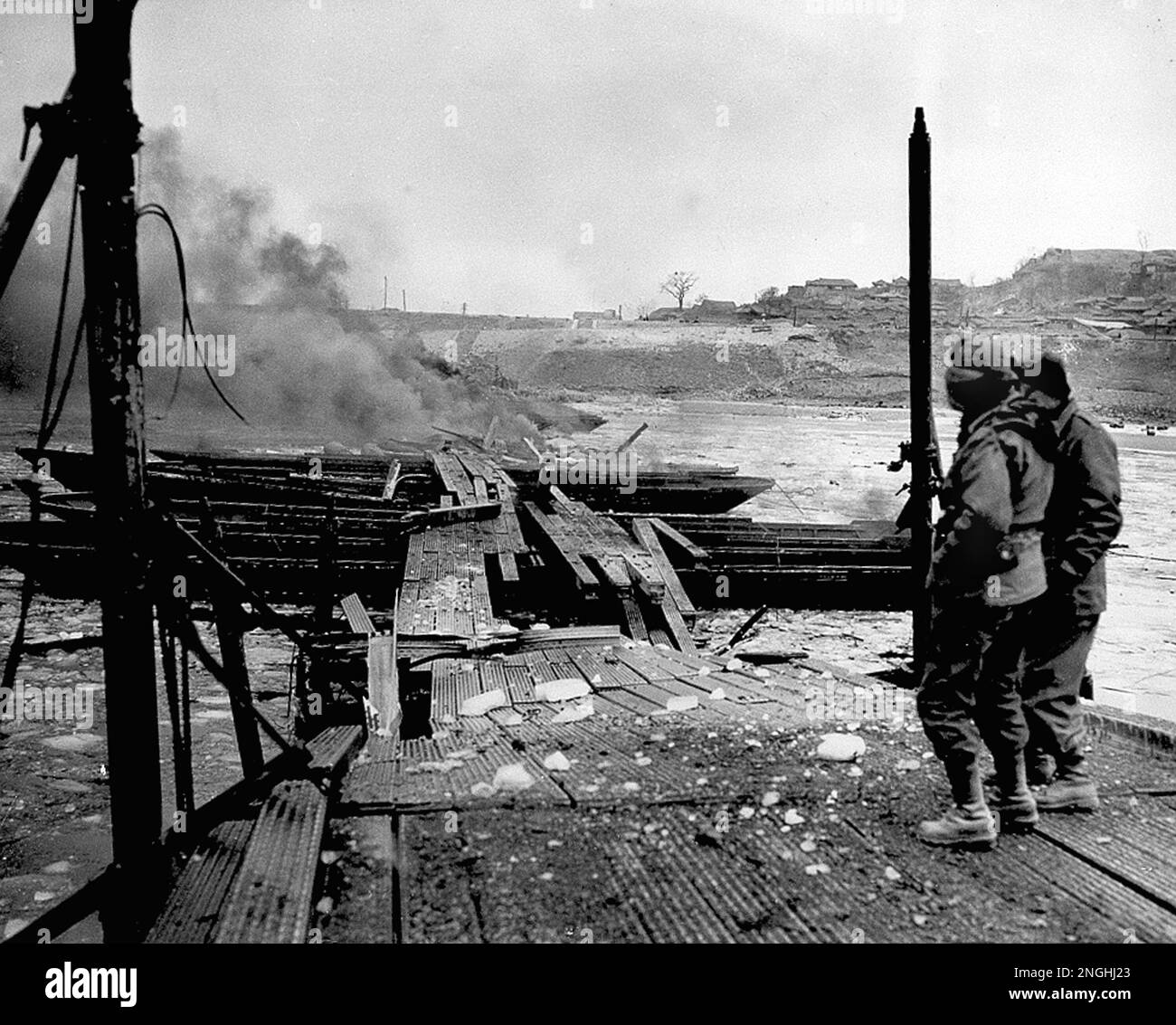 United Nations soldiers watch flames consume a pontoon bridge across ...