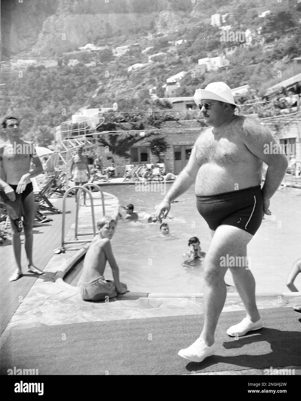 Exiled Egyptian King Farouk strolls in the sun by the swimming pool at singer Gracie Fields ...