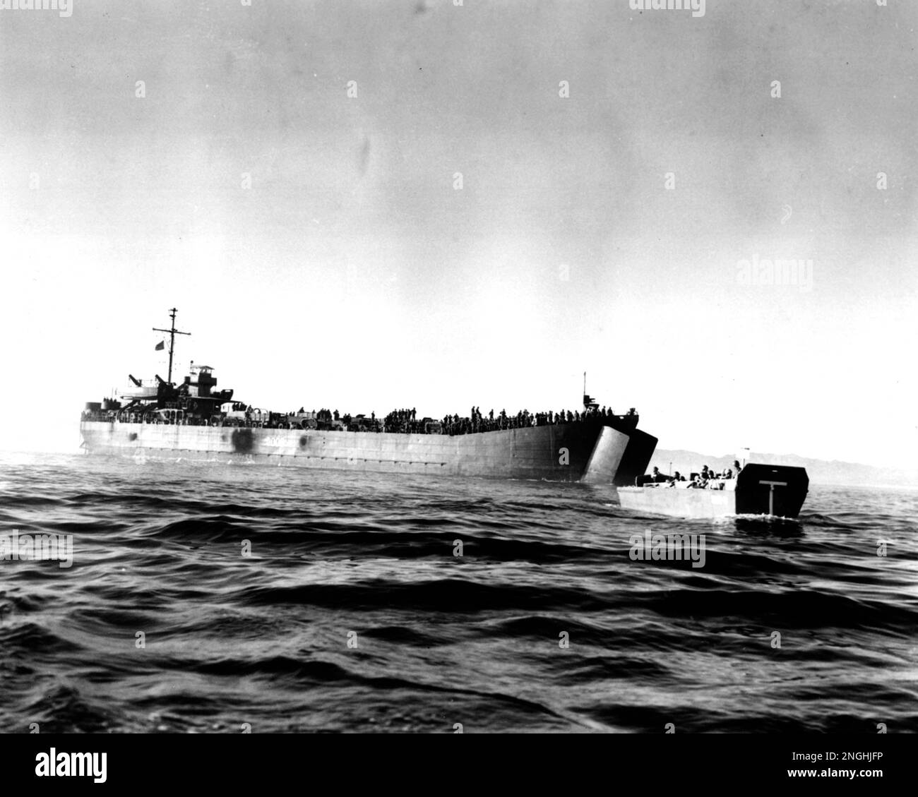 A small landing craft, launched by the LST behind, carrying U.S. troops ...