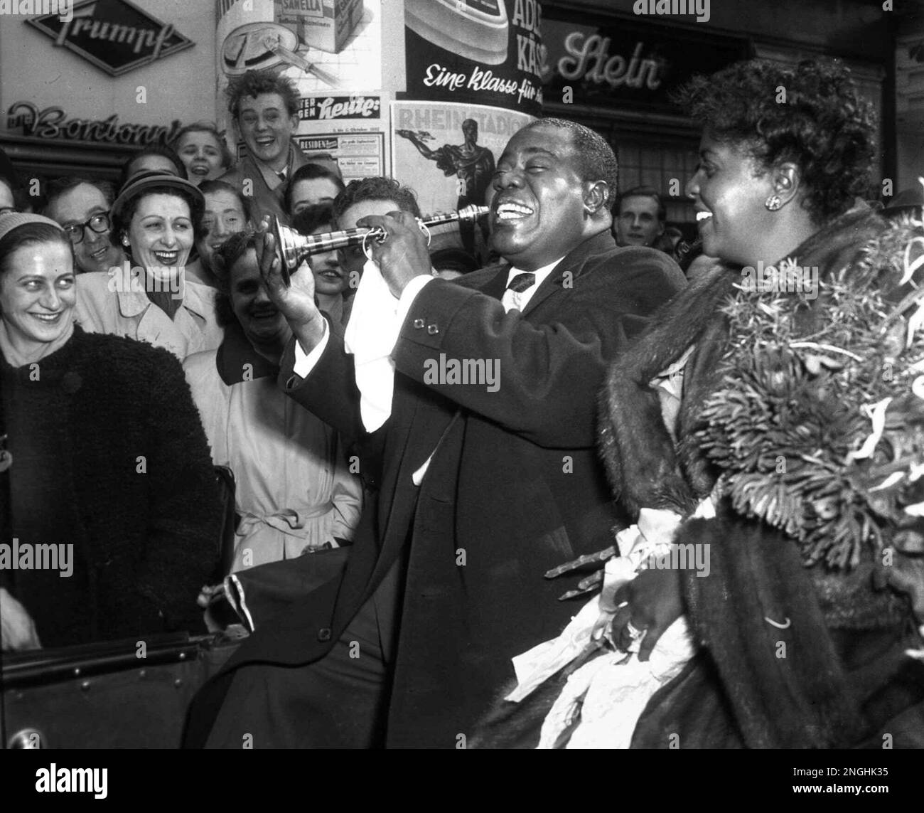Jazz great Louis Armstrong plays a child's trumpet as he receives a ...