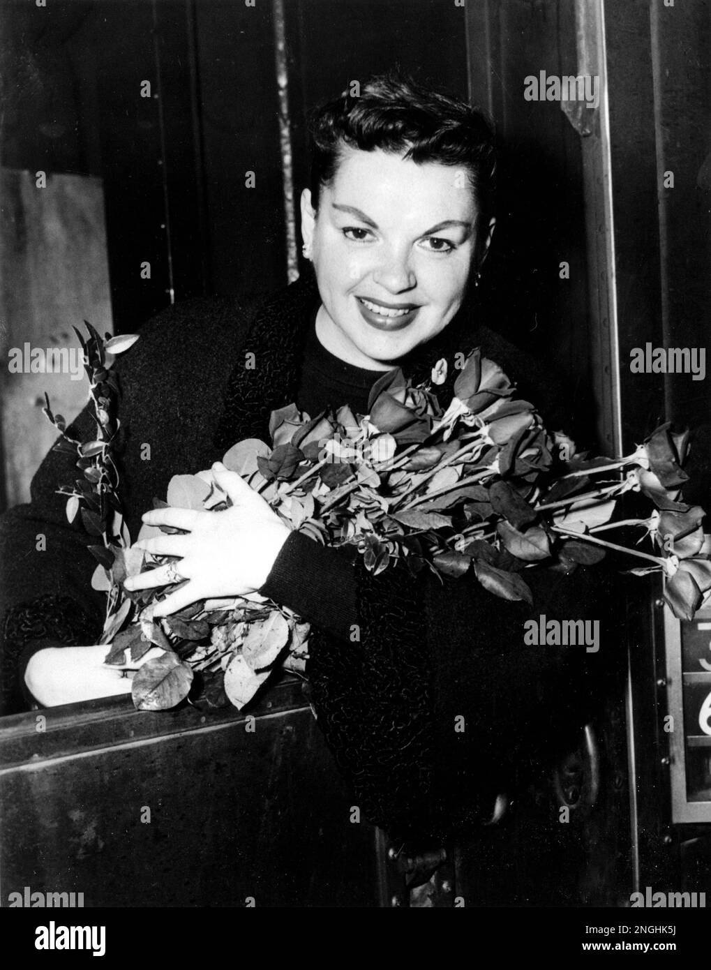 Judy Garland poses with long-stemmed roses in her arms as she arrives ...