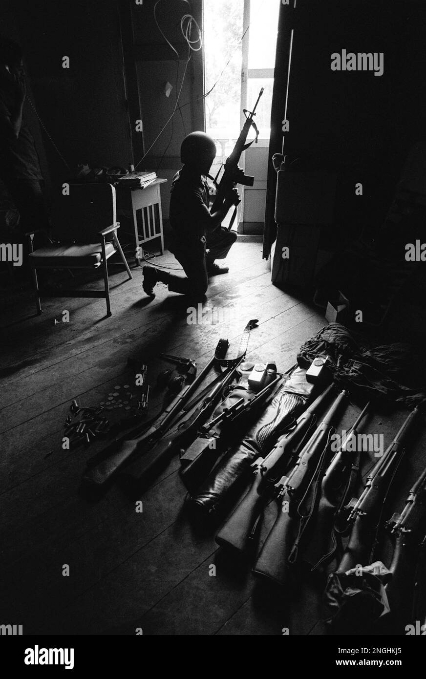 With captured rebel weapons spread out on the floor, a member of the ...