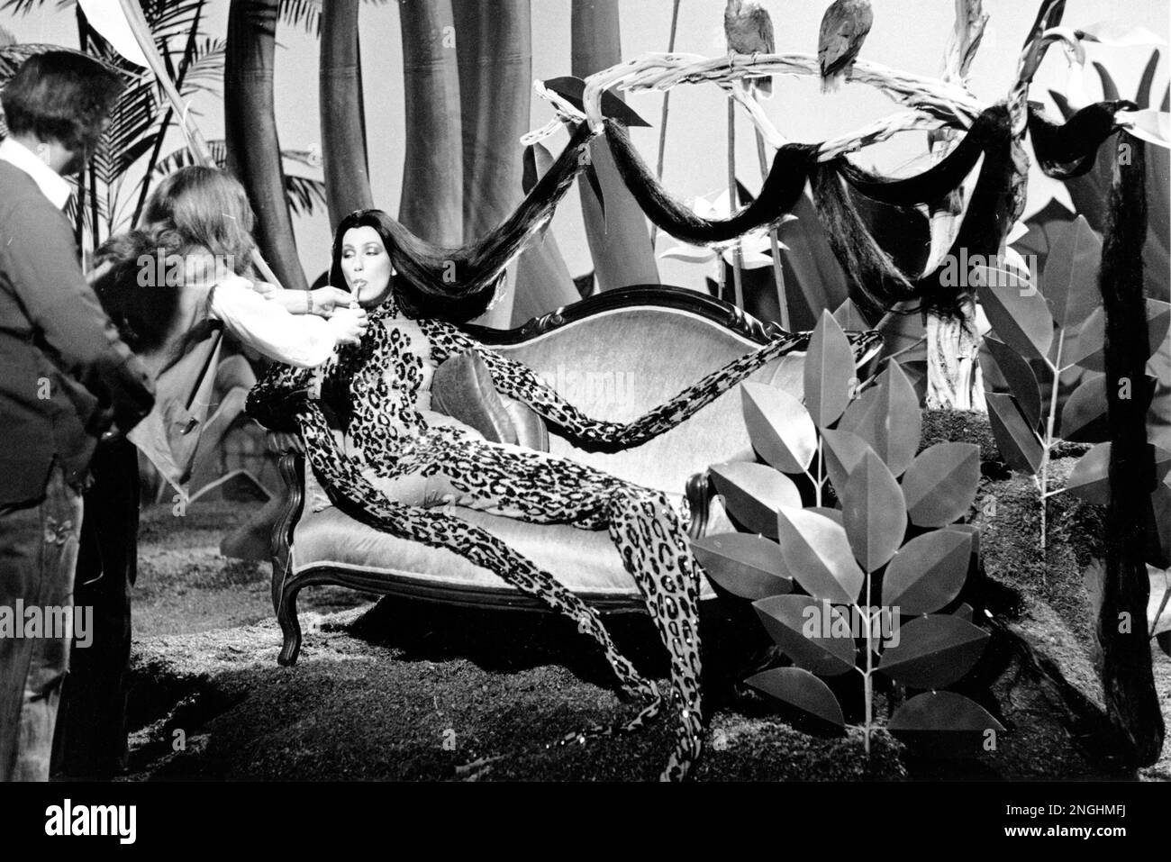 Entertainer Cher is fed a drink of water through a straw by a stagehand ...