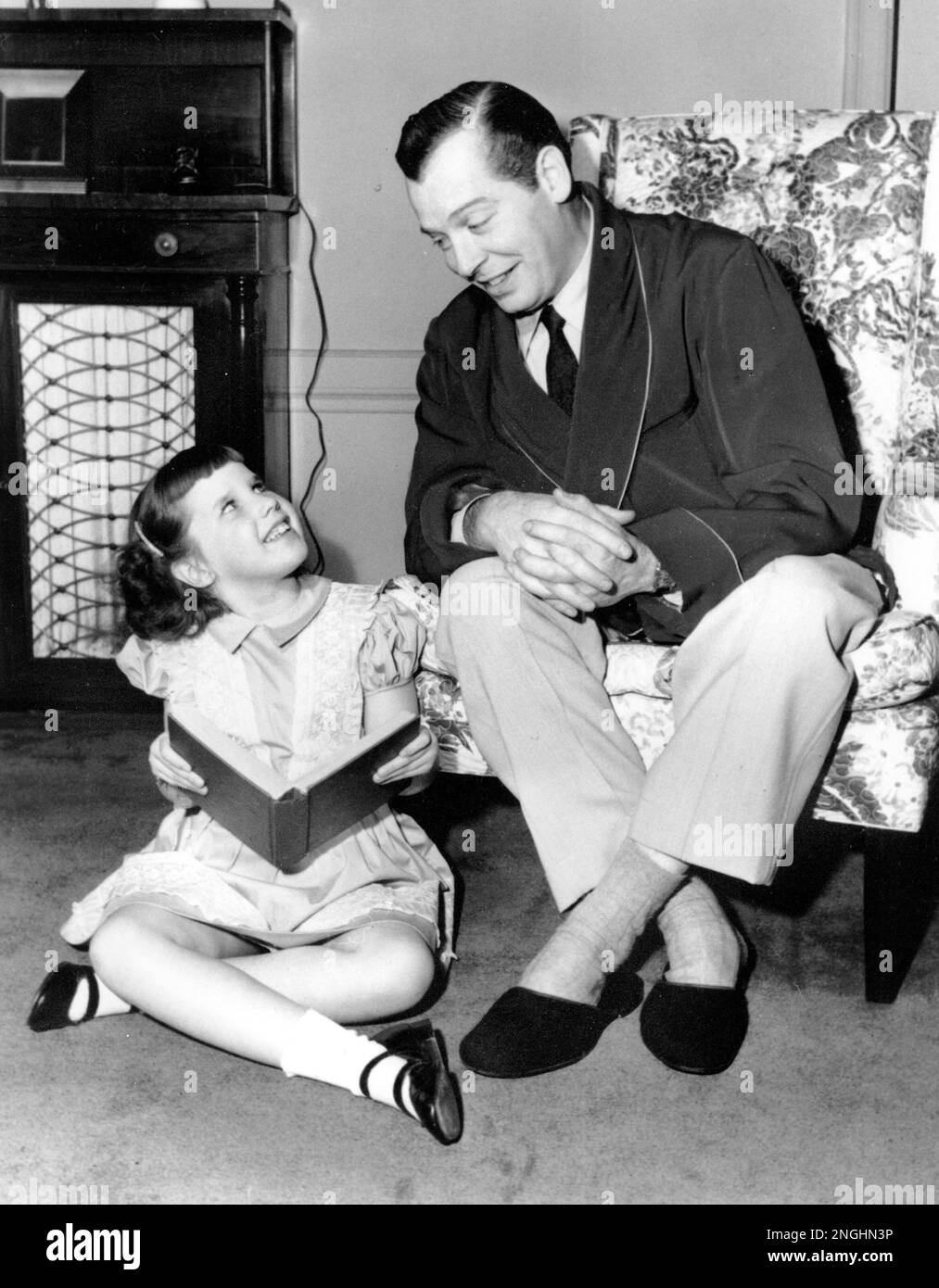 Milton Berle smiles at his daughter, Vickie, who reads him a story on ...