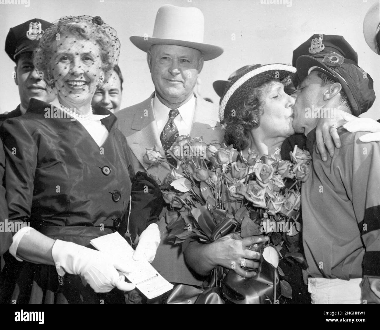 Jockey Eddie Arcaro is kissed by his mother, Josephine, holding roses ...