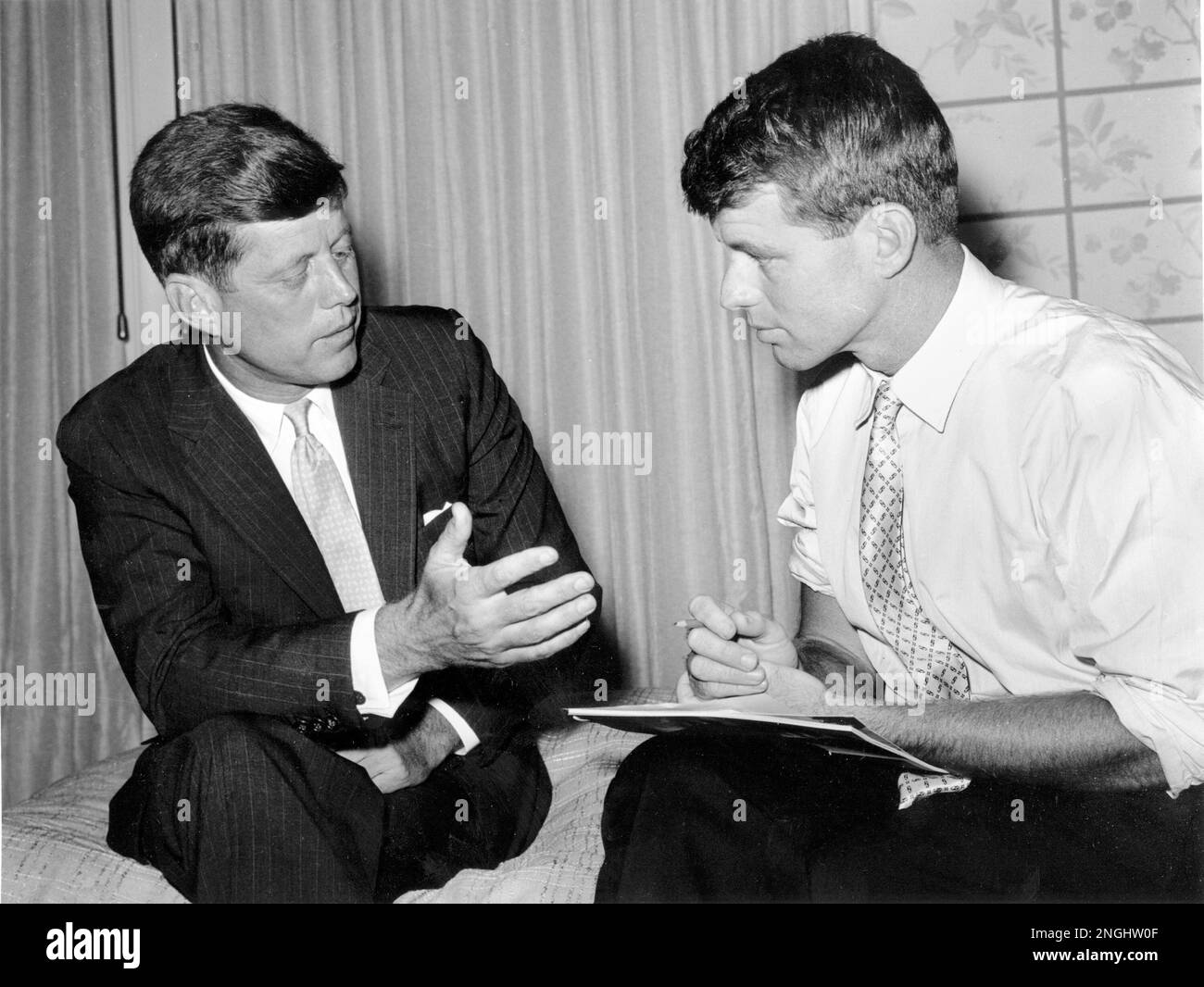Massachusetts Sen. John F. Kennedy, left, compares notes with his ...