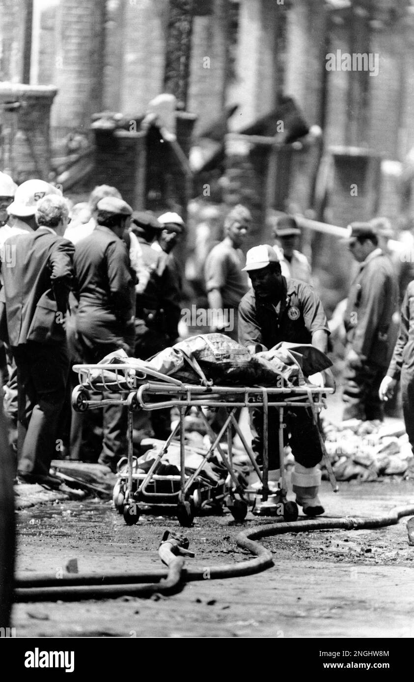 A worker pushes a stretcher carrying a body recovered from the rubble ...