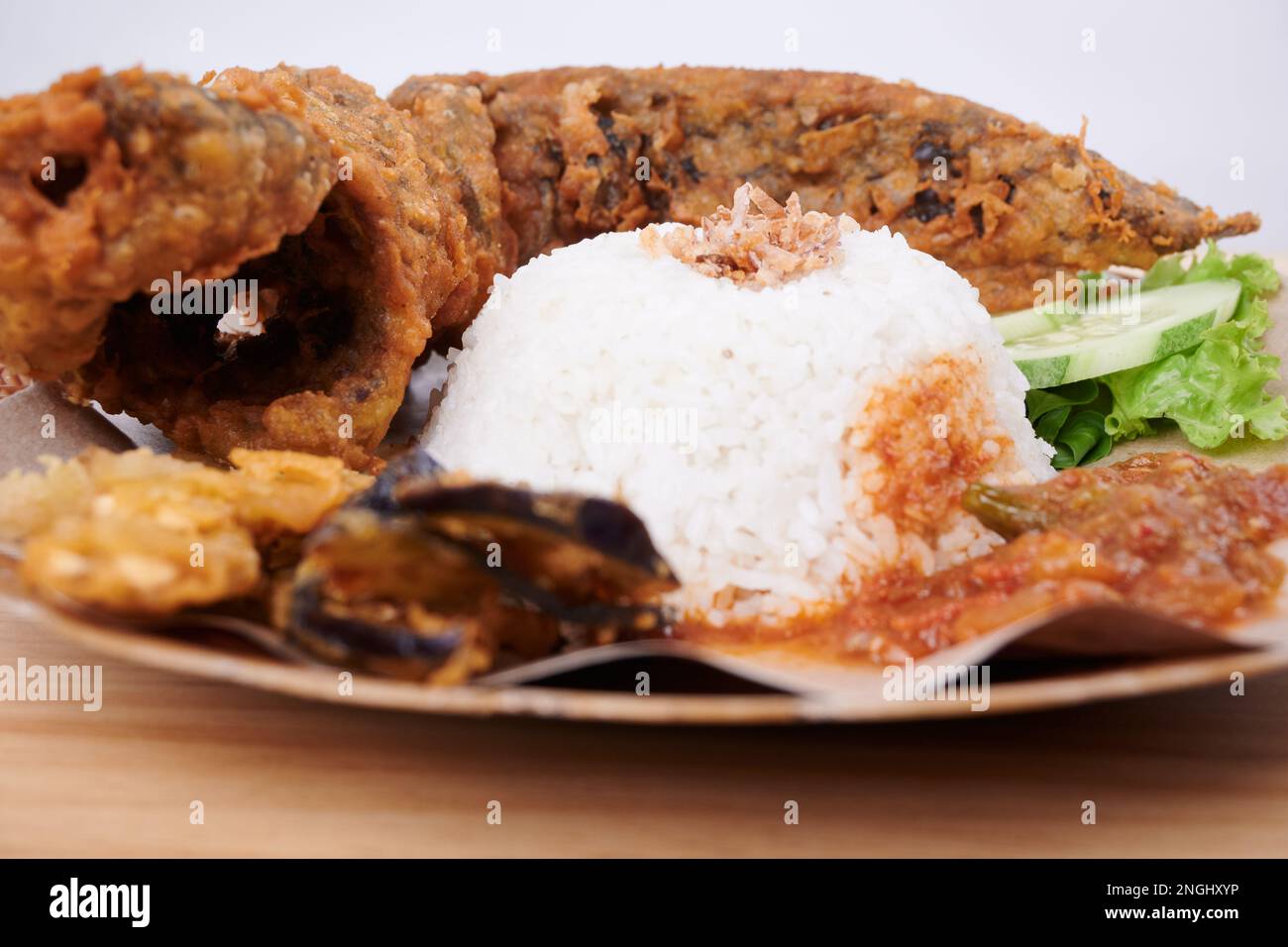 Fried Catfish with Spicy Sauce, rice and vegetables on a plate (Pecel ...