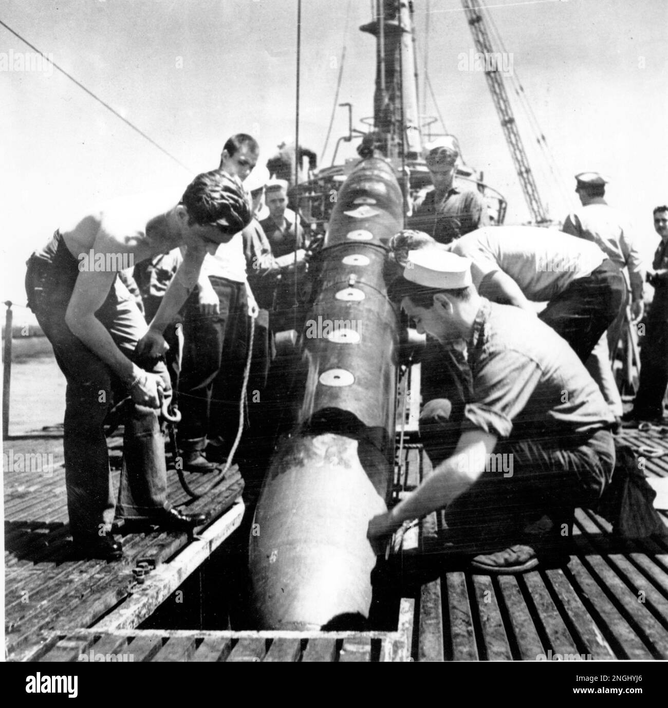 U.S. Naval crew members of a submarine stow away below deck a torpedo ...