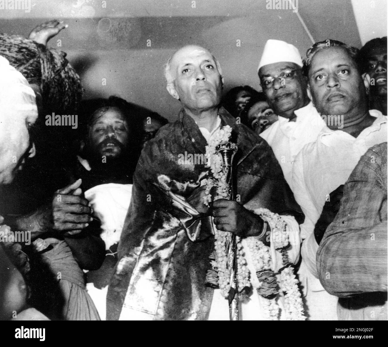 Prime Minister of India Jawaharlal Nehru, center, holds a mace of gold ...