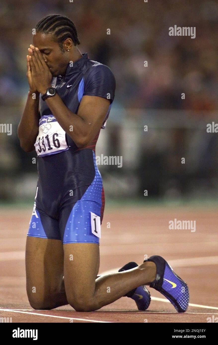 U.S. hurdler Angelo Taylor kneels on the track after winning the gold ...