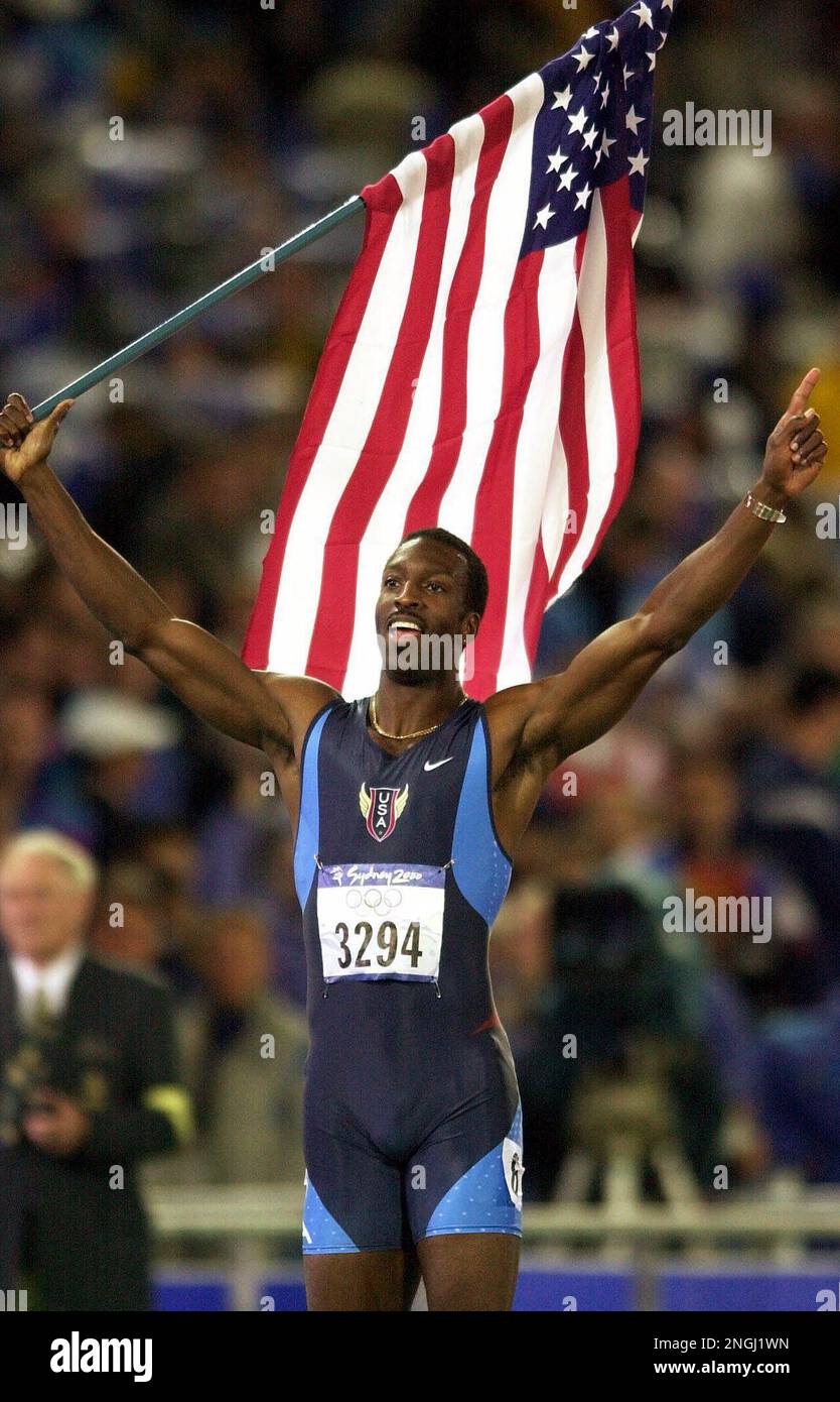 U.S. sprinter Michael Johnson carries the U.S. flag after winning the ...