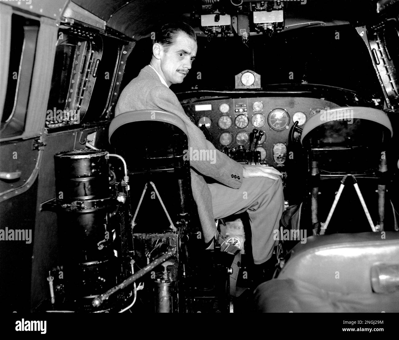 American aviator Howard Hughes sits in the pilot's compartment of a ...