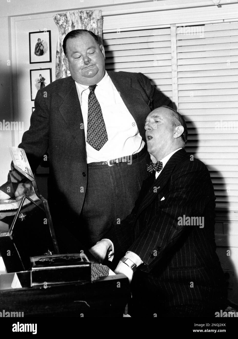 Comedic actors Stan Laurel, seated, and Oliver Hardy pose in an office ...