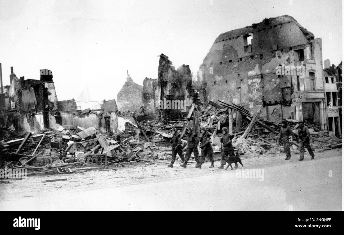 American soldiers walk through a street in war-torn Bastogne, Belgium ...