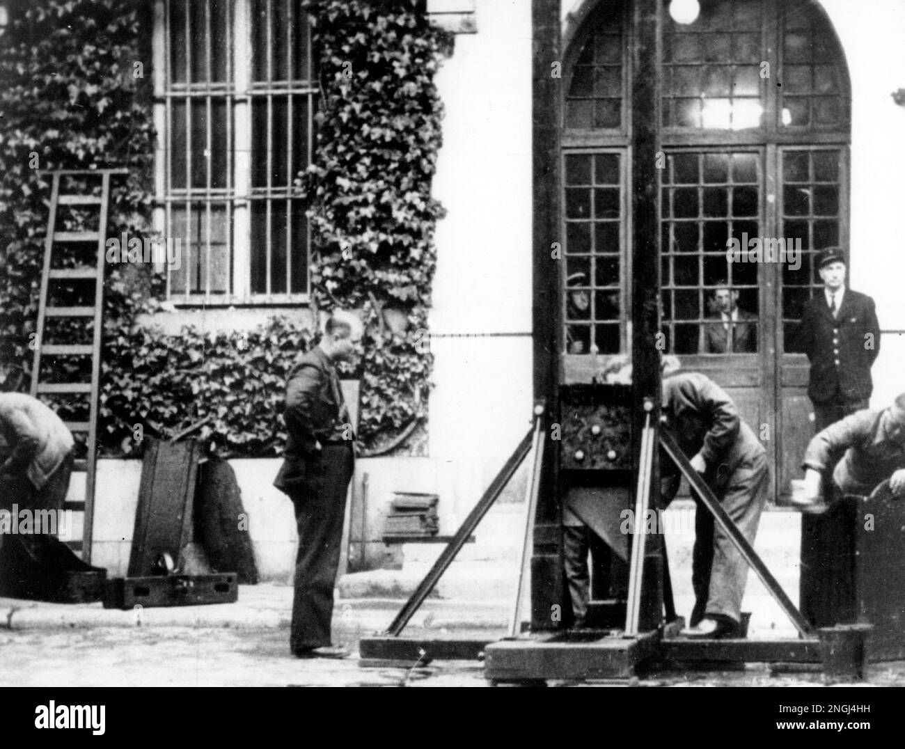 Workmen in the Sante Prison court yard clean and dismantle a guillotine ...