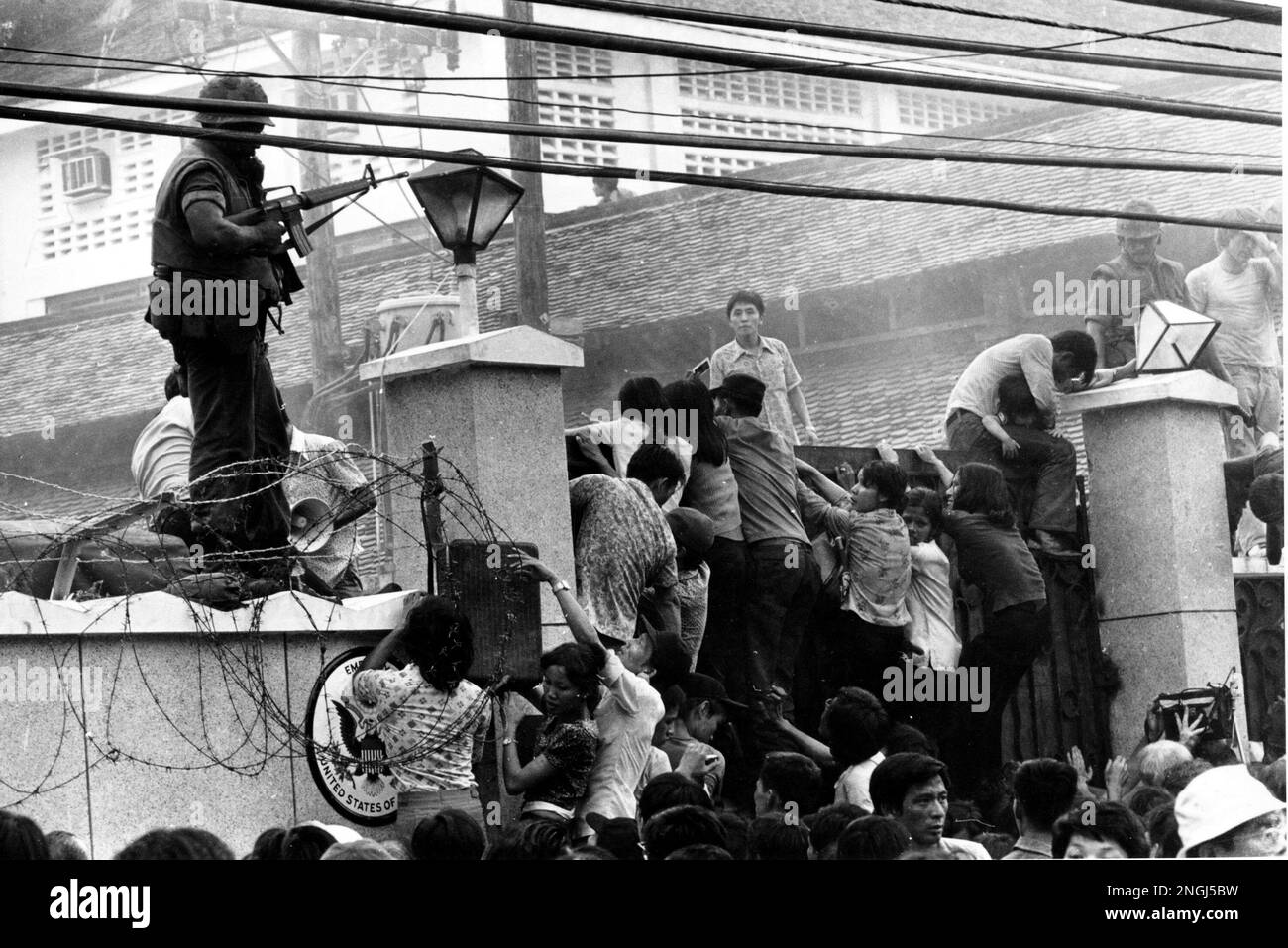 Mobs of Vietnamese people scale the wall of the U.S. Embassy in Saigon ...
