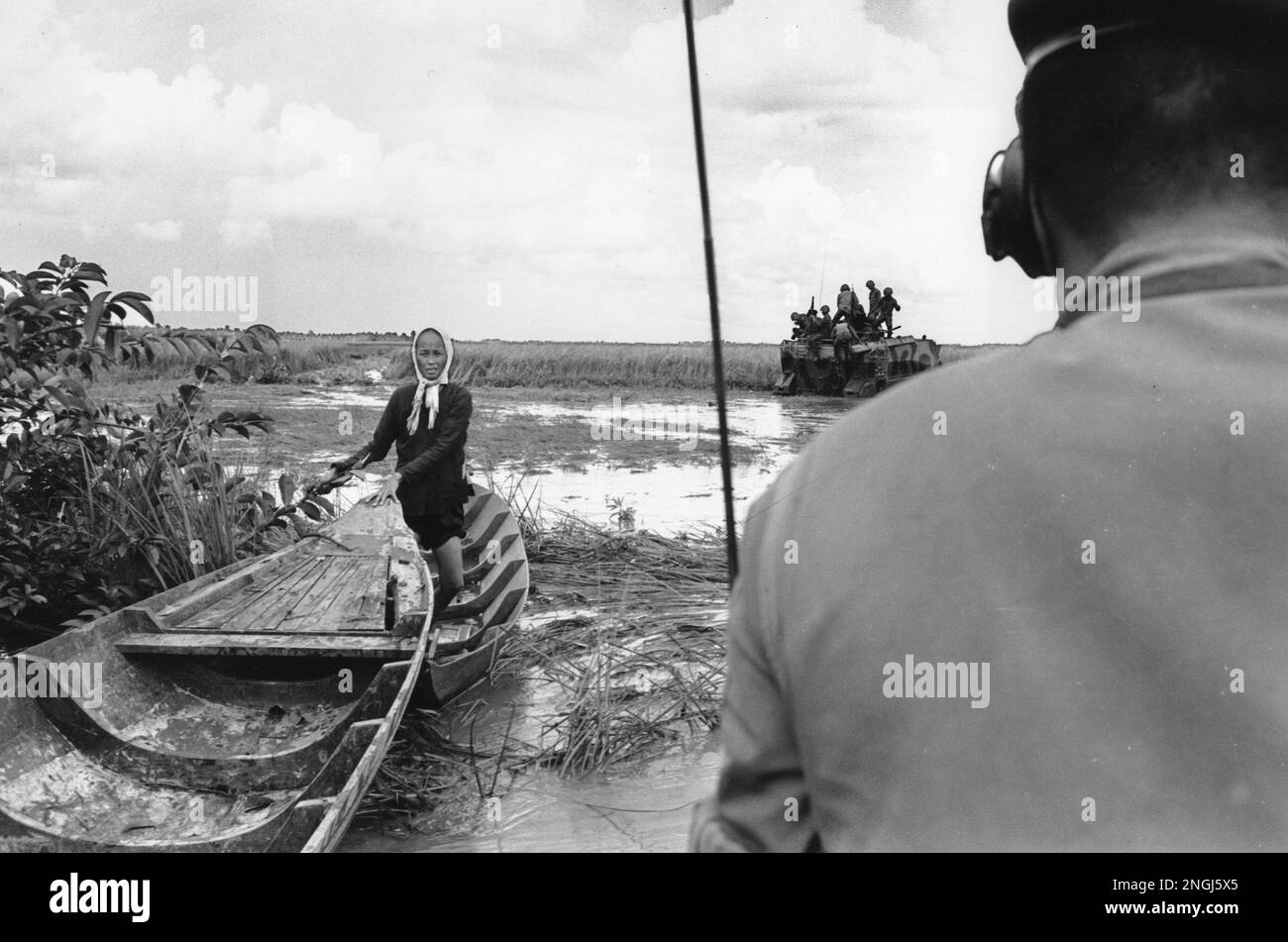 This photo shows a woman standing in a boat in a rice paddy field while ...