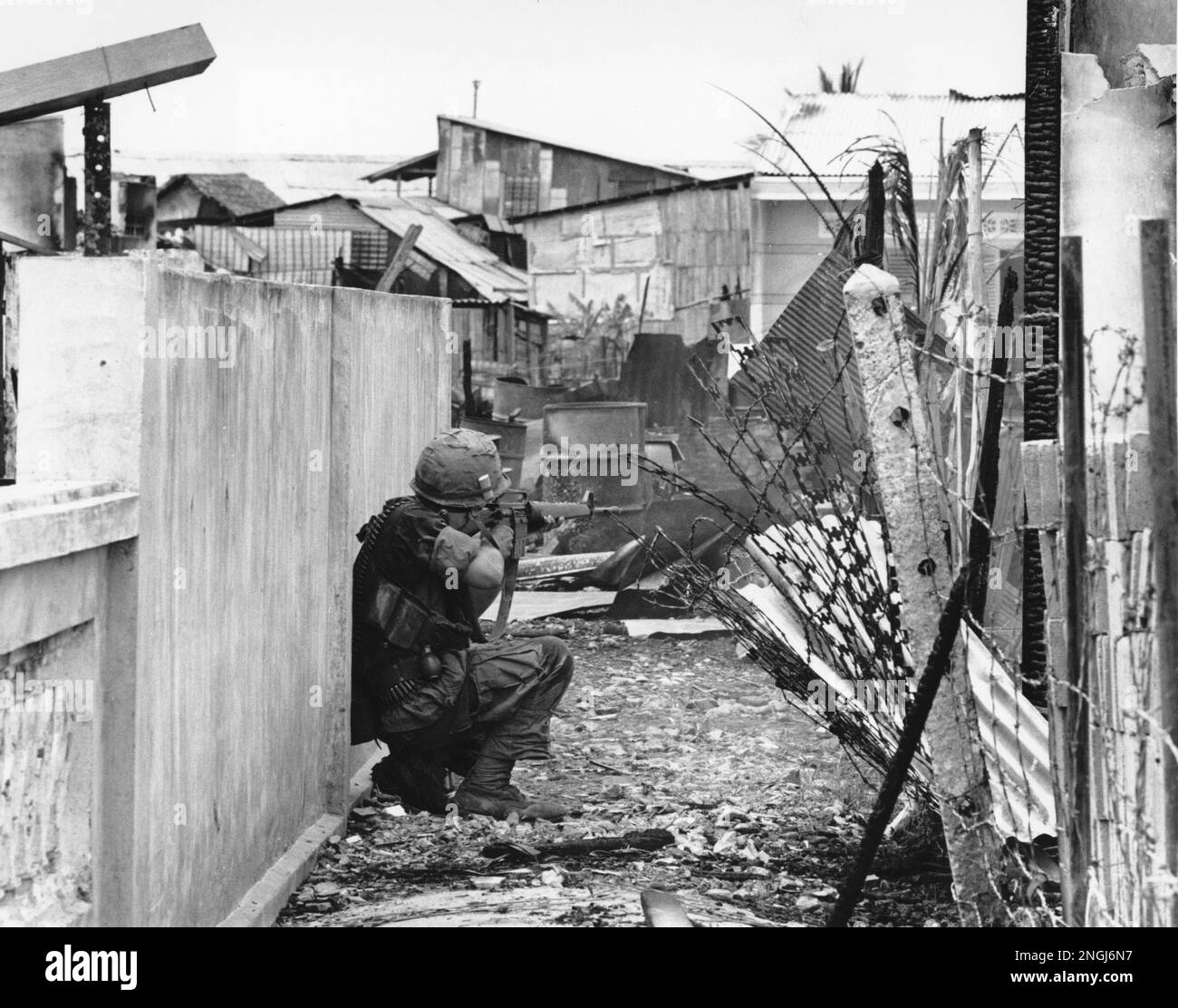 A U.S. Marine aims at a North Vietnamese bunker while two other G.I.s ...